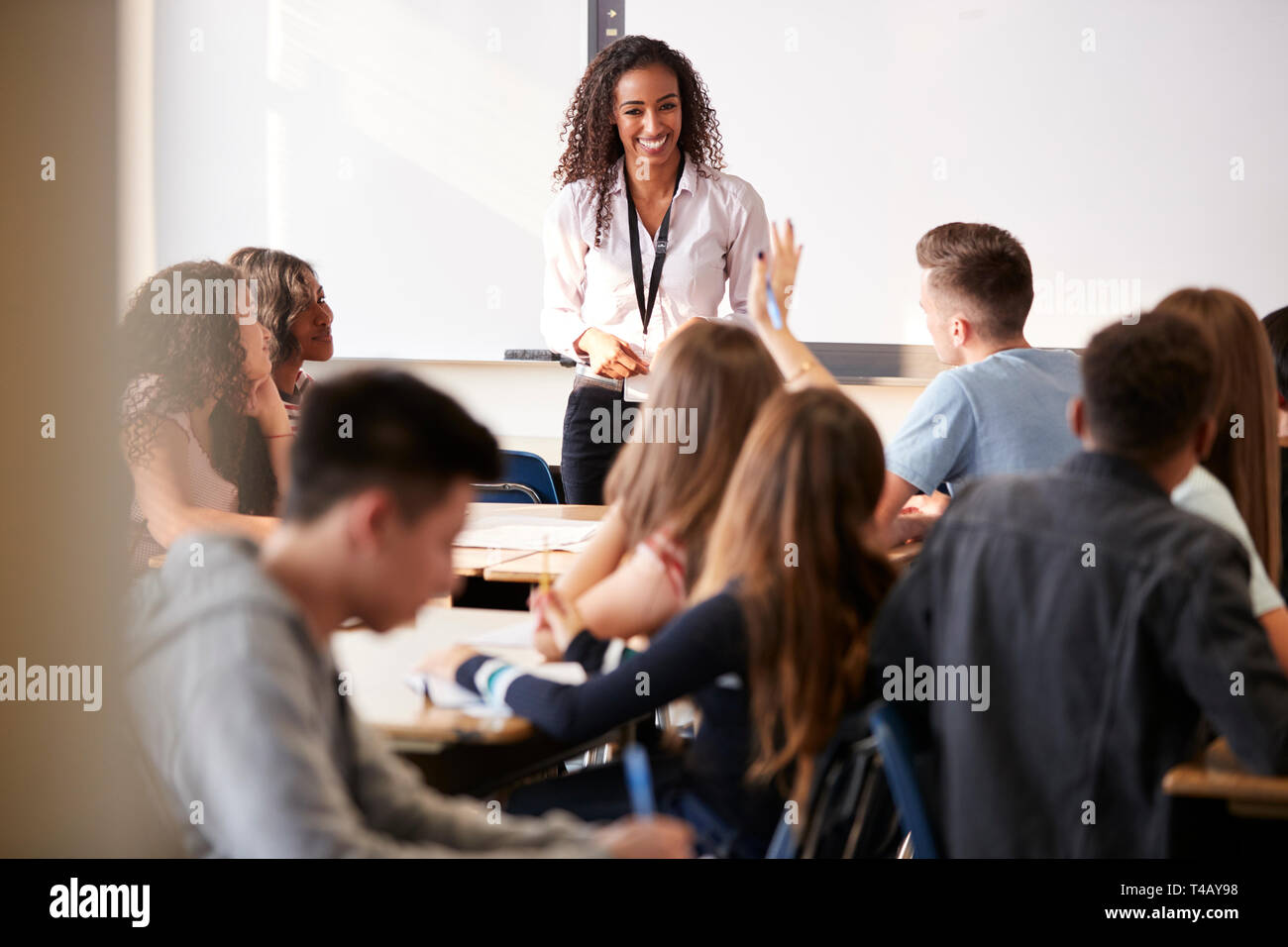 Female High School Teacher Standing In Front Of Interactive Whiteboard