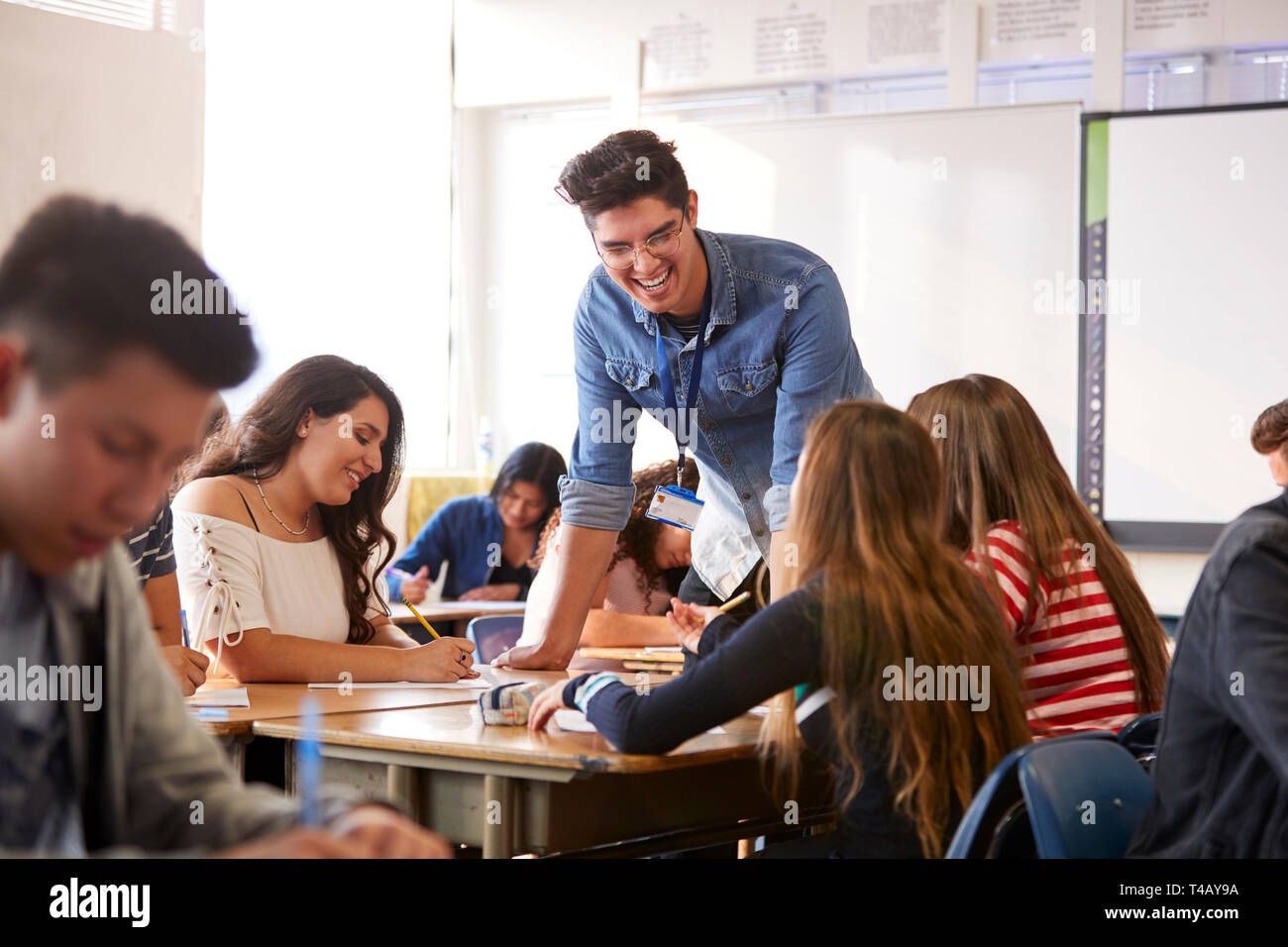 Male High School Teacher Standing By Student Table Teaching Lesson ...