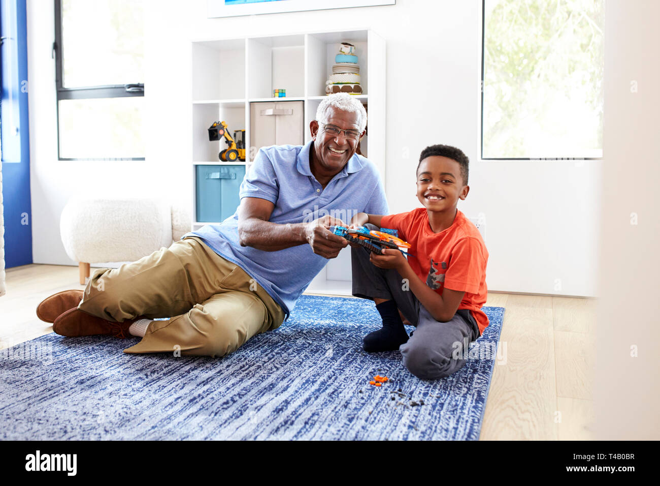 Portrait Of Grandfather With Grandson Lying On Rug At Home Building ...