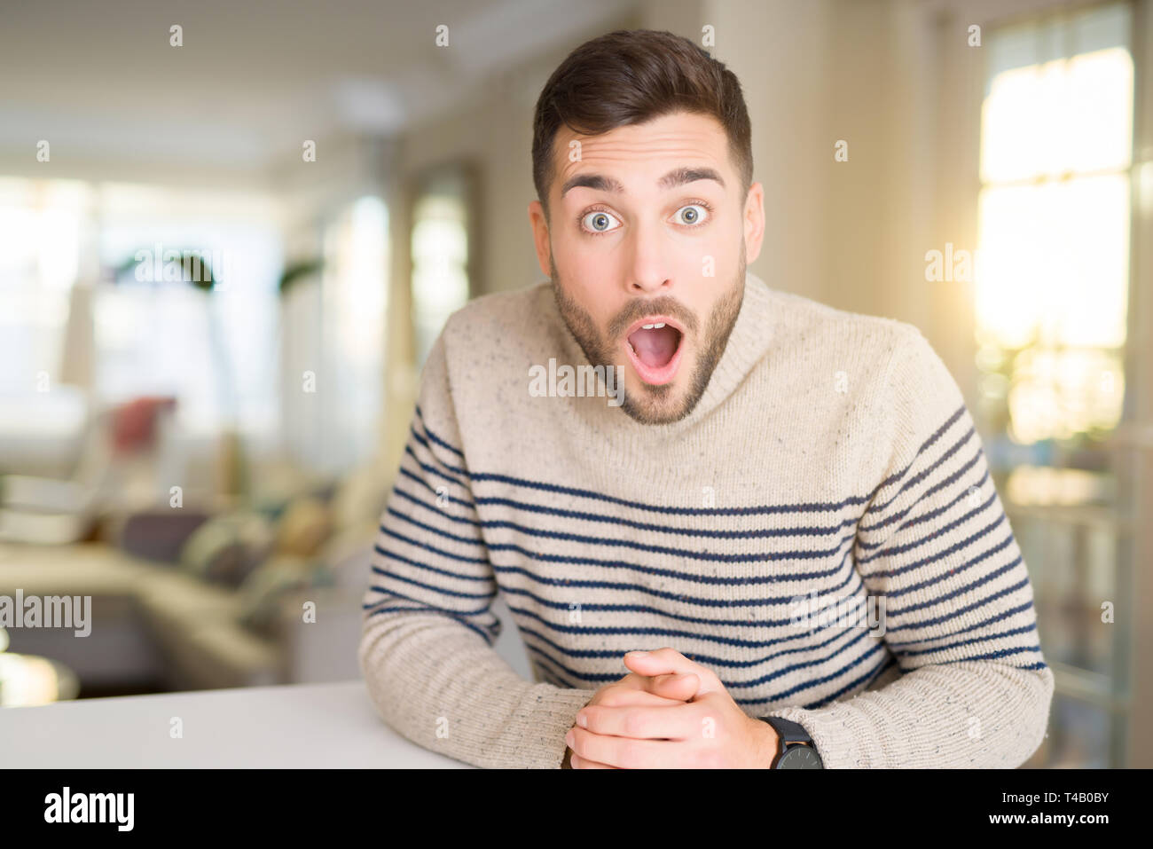 Young handsome man at home afraid and shocked with surprise expression, fear and excited face ...