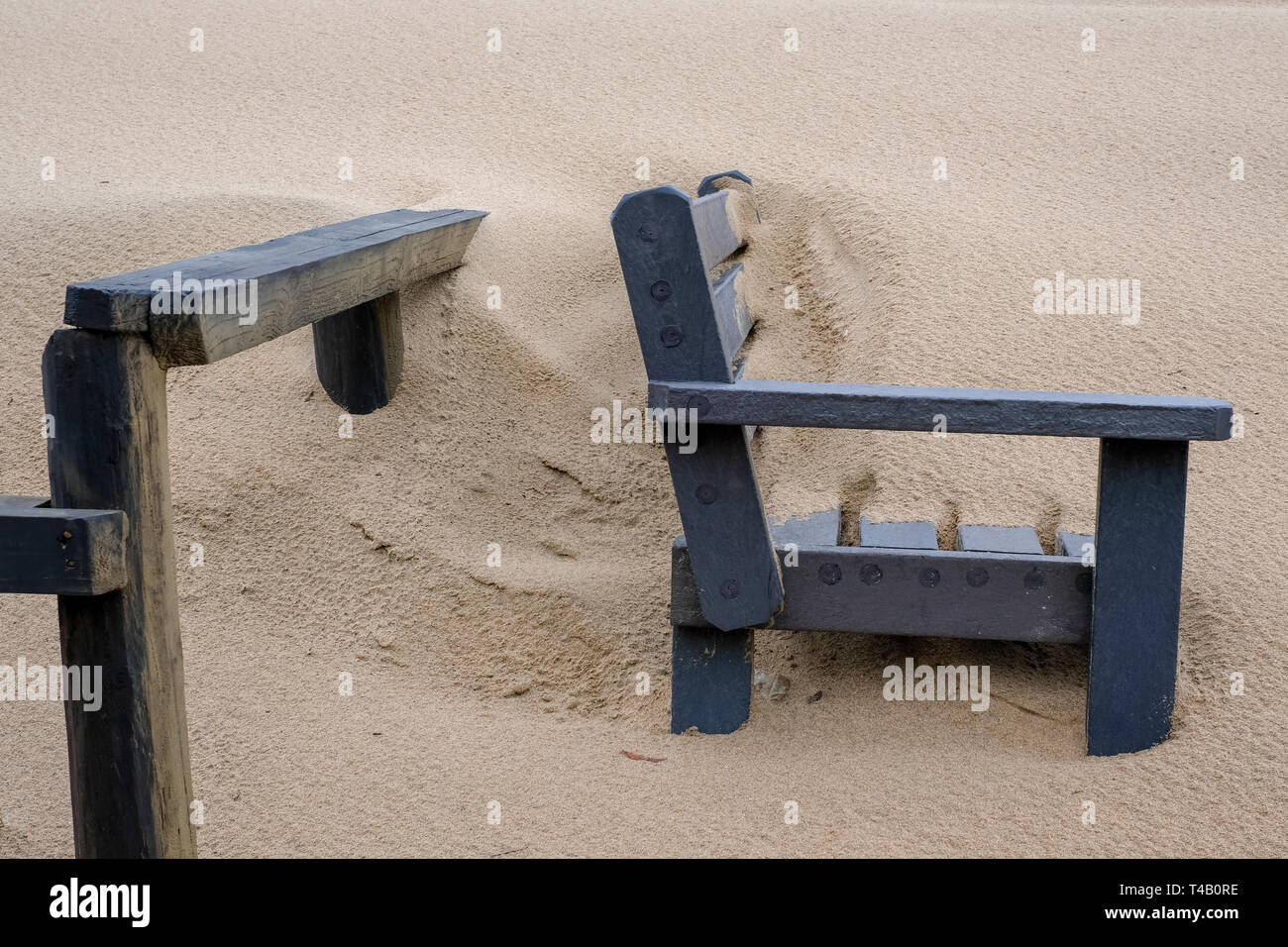 Wooden bench is covered in sand on the beach at Boggams Bay on the ...
