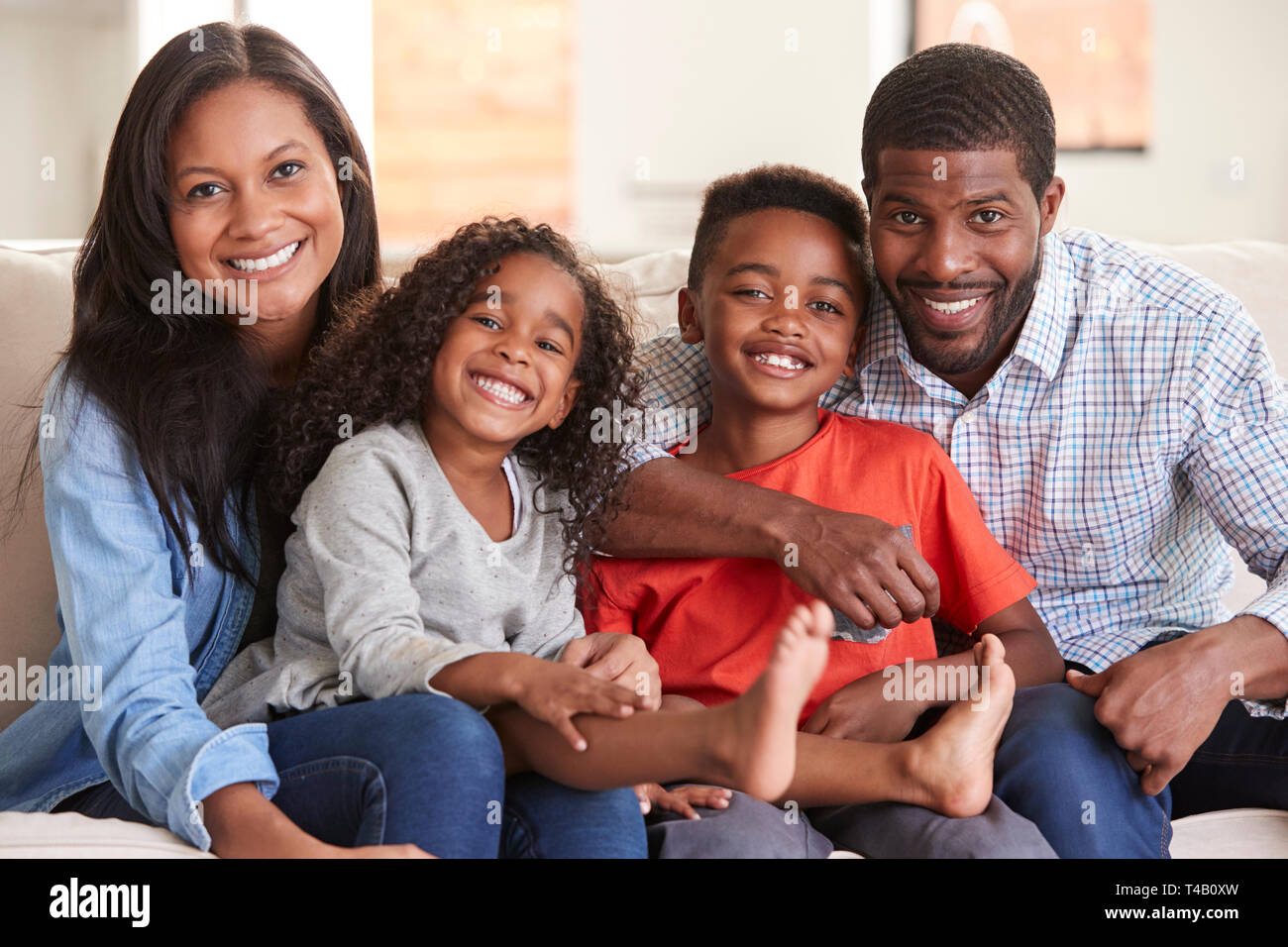 Portrait Of Family Sitting On Sofa At Home Smiling At Camera Stock ...