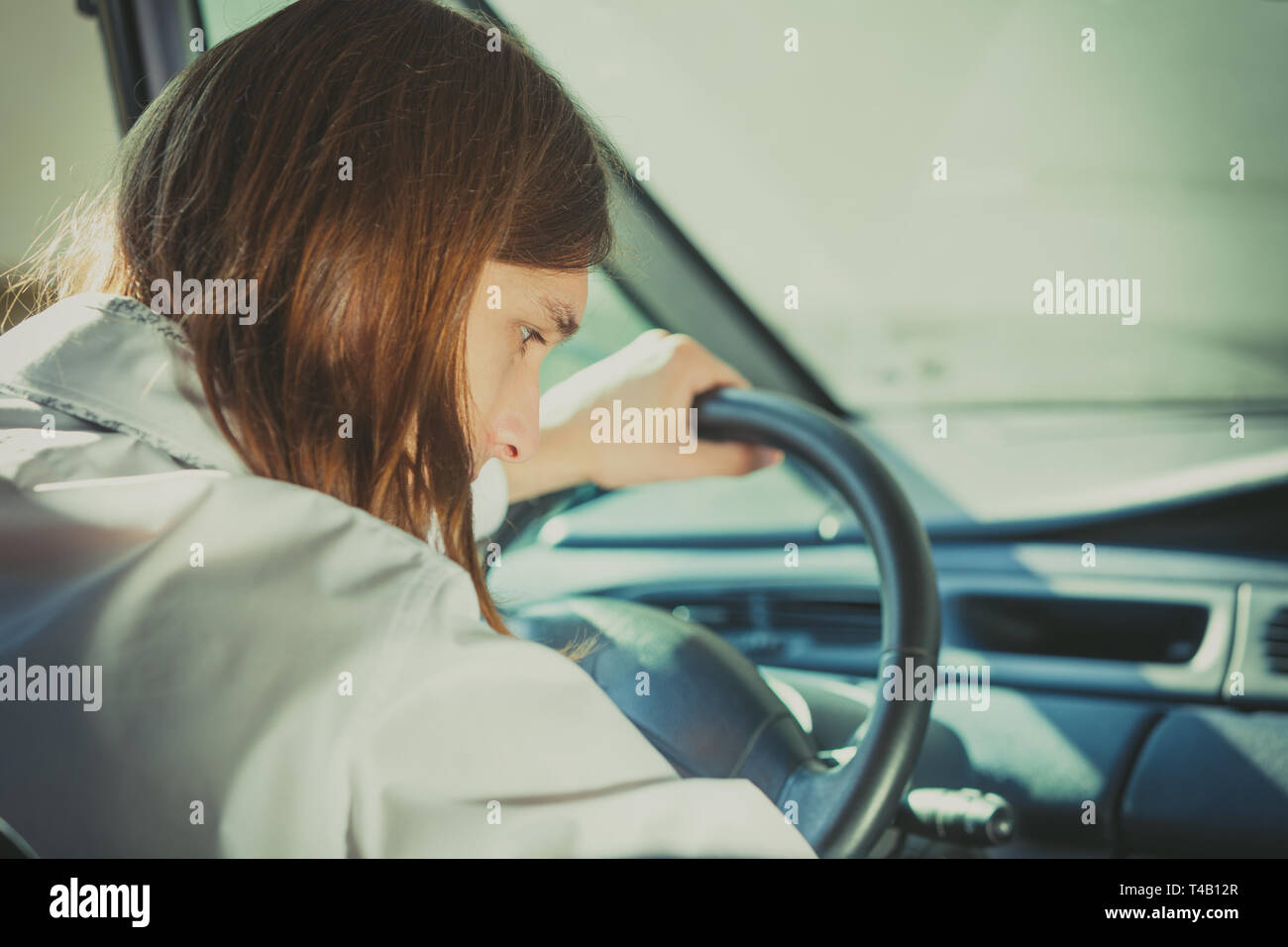 Young man driver wearing white shirt having long hair, driving car ...