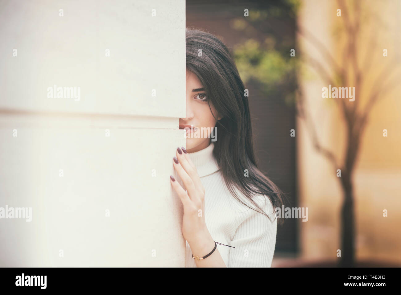 Scared young woman hiding outdoors Stock Photo - Alamy