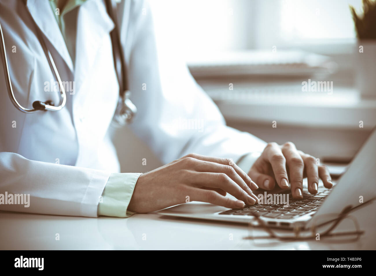 Doctor woman using laptop computer while sitting at the desk near ...