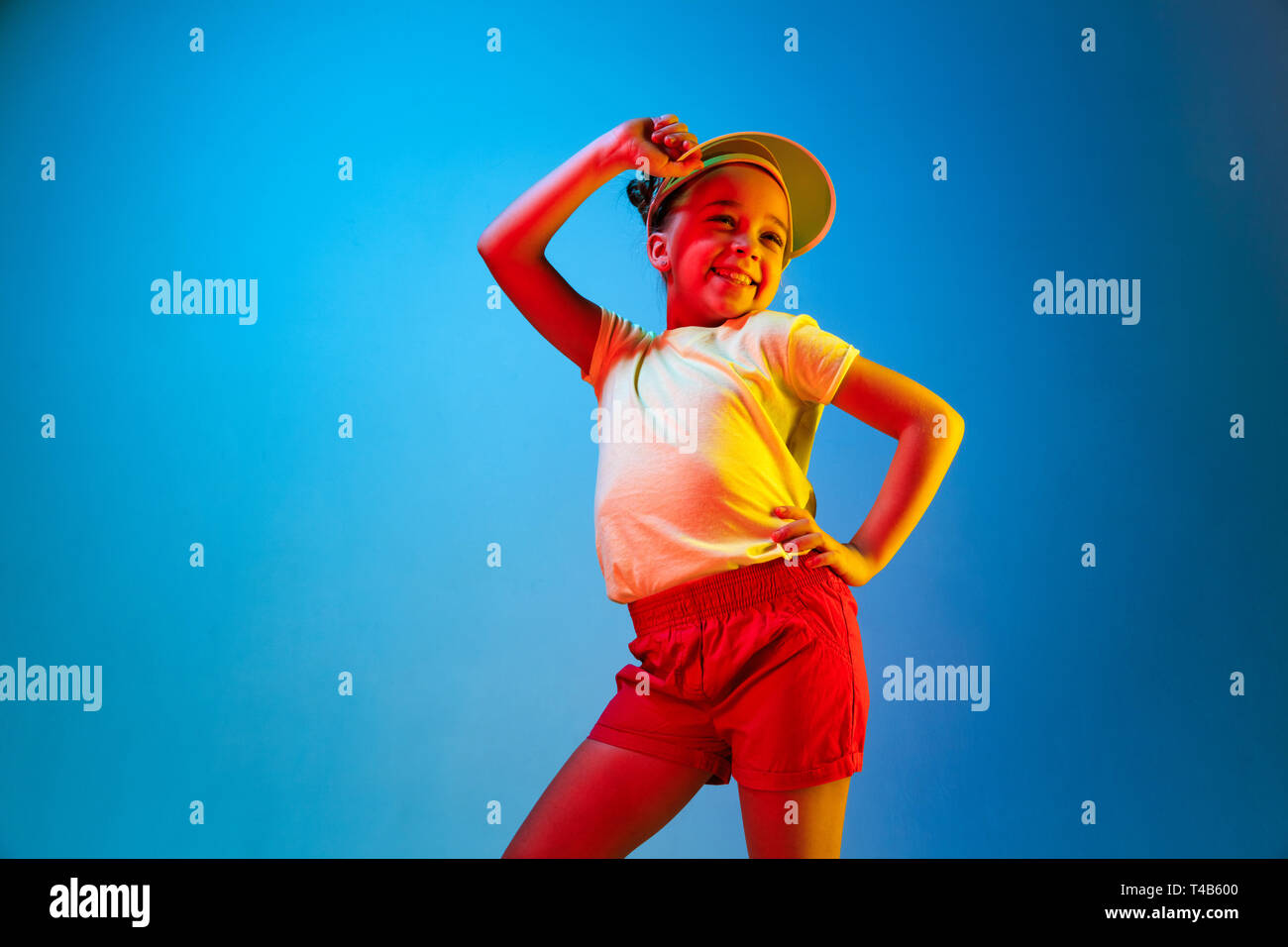 Happy teen girl standing and smiling isolated on trendy blue neon ...