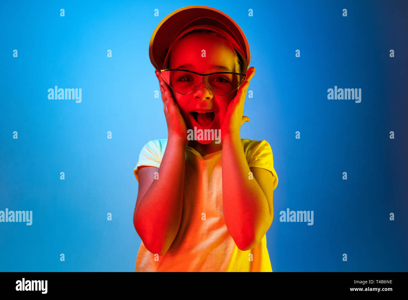 Happy teen girl standing and smiling isolated on trendy blue neon ...