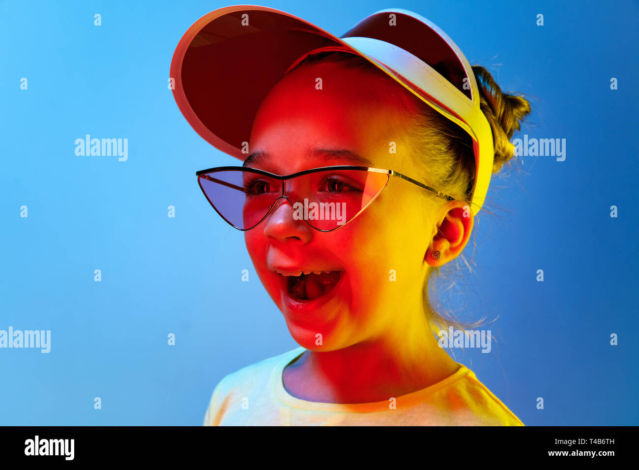 Happy teen girl standing and smiling isolated on trendy blue neon ...