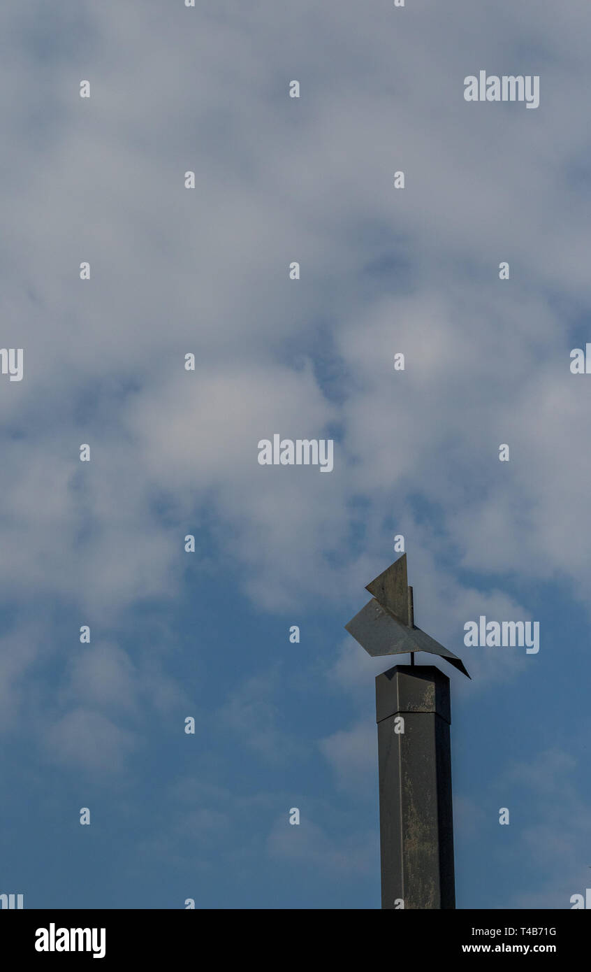 A chimney with a wind vane on top isolated against a blue and cloudy ...
