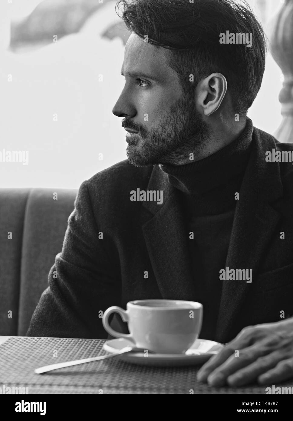 Thinking handsome man sitting in cafe and drinking cup of coffee on the ...