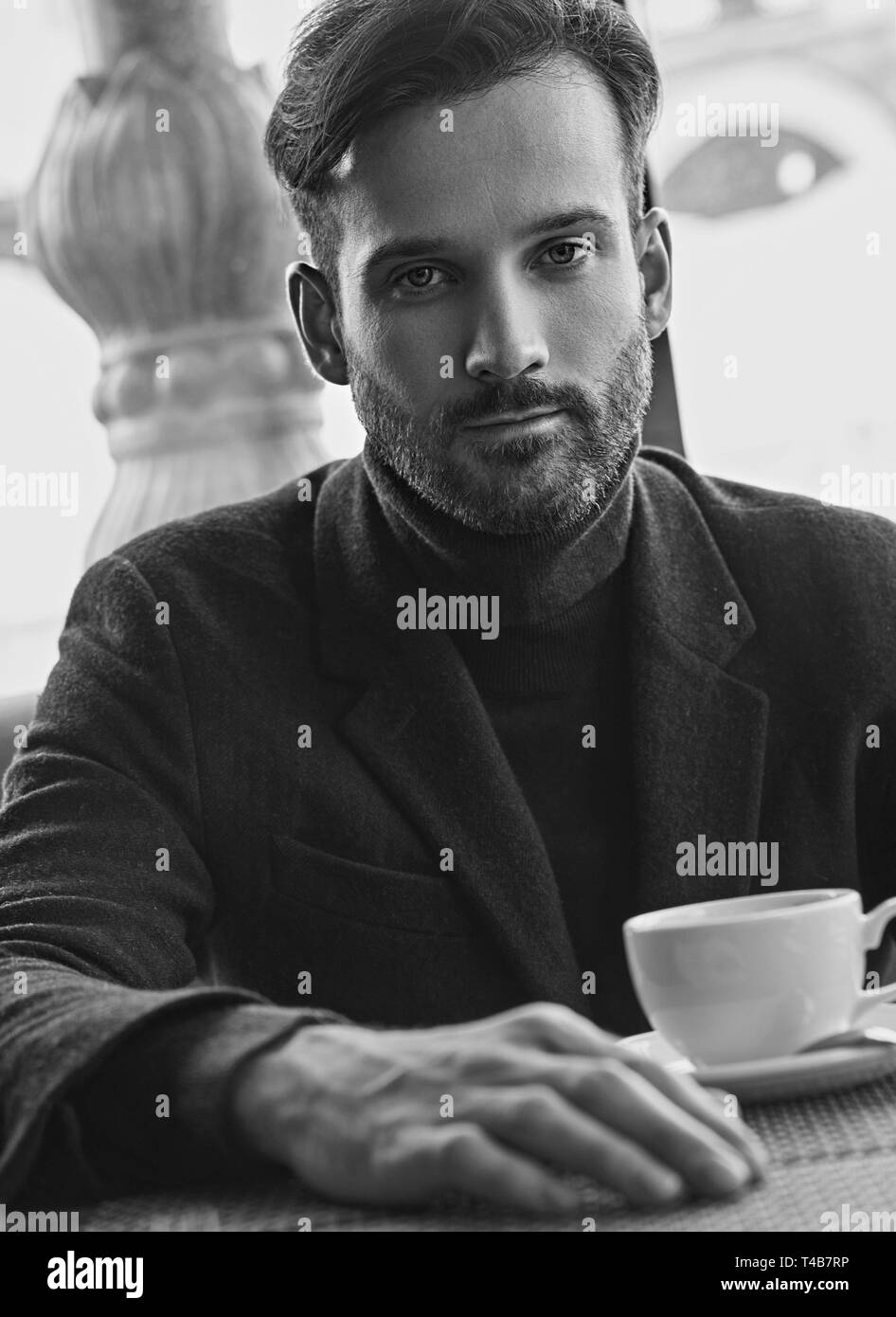 Thinking handsome man sitting in cafe and drinking cup of coffee on the ...