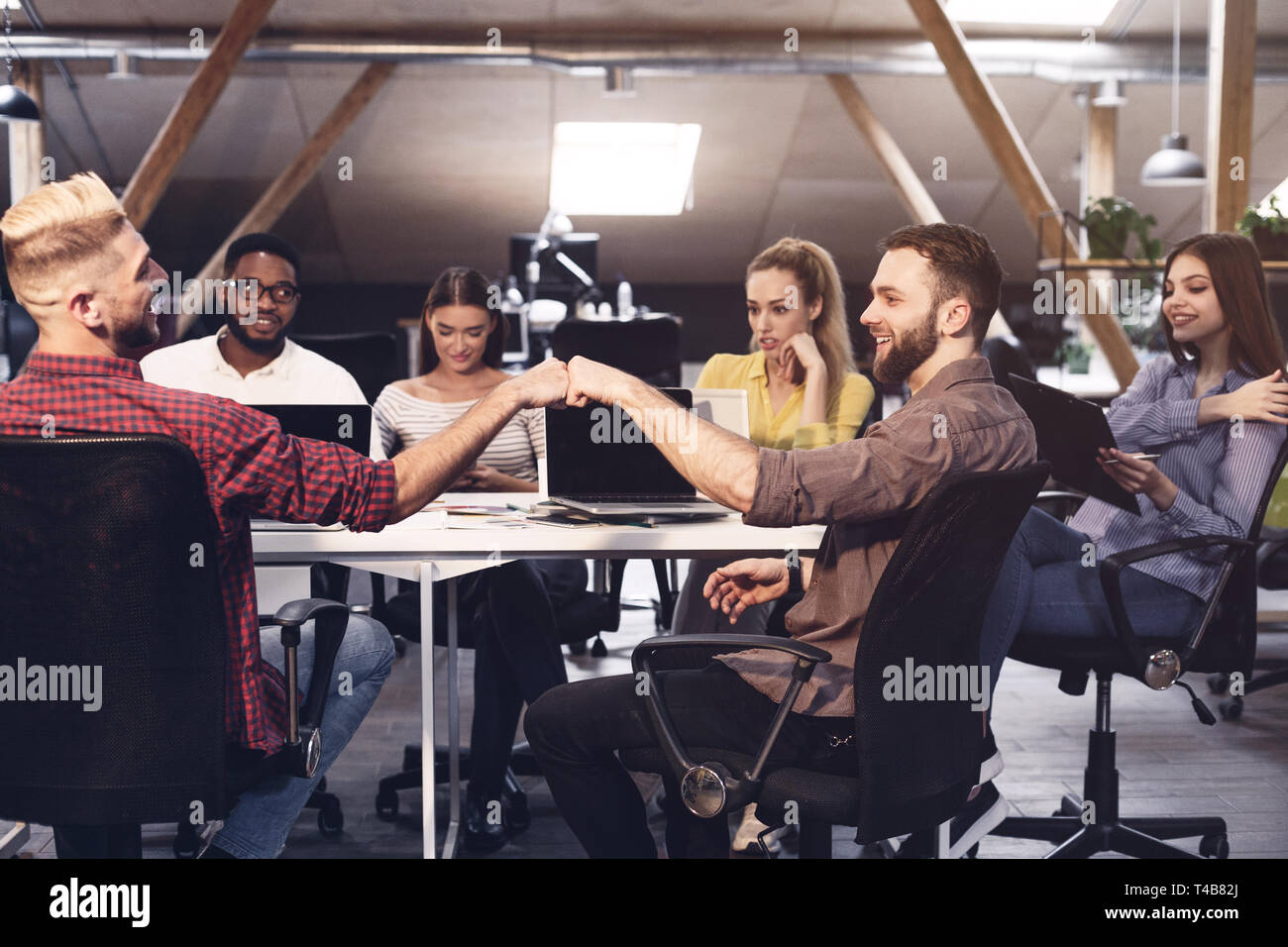 Friendly colleagues bumping fists at workplace, celebrating good ...