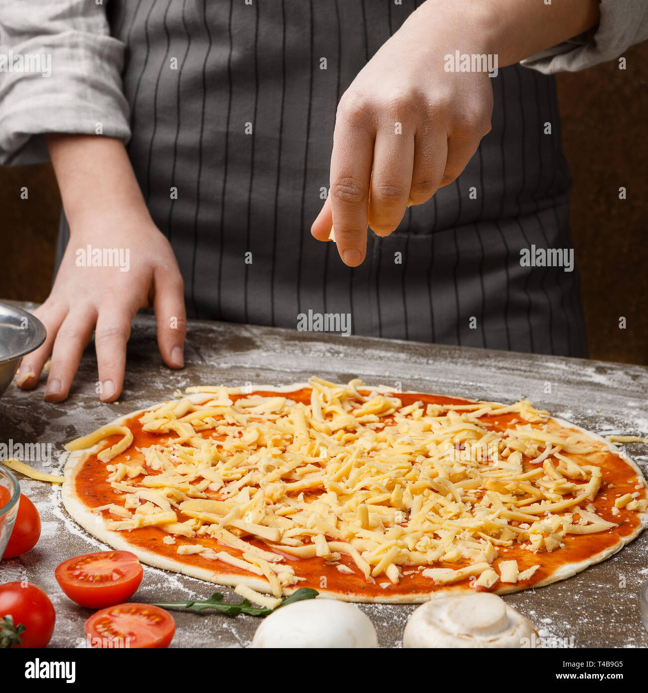 Chef sprinkling pizza with cheese at kitchen Stock Photo - Alamy
