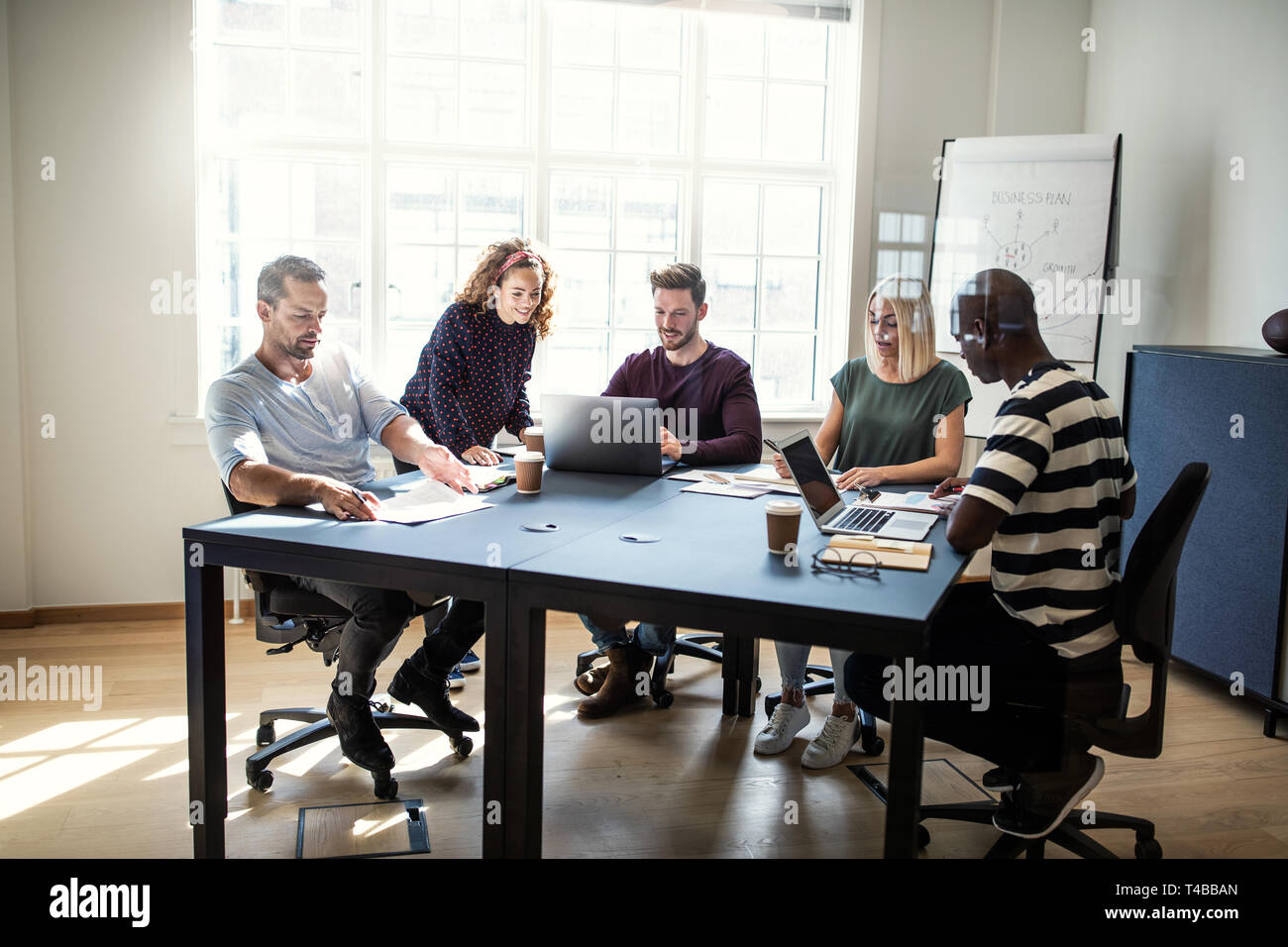 Diverse group of smiling designers working together around a boardroom ...