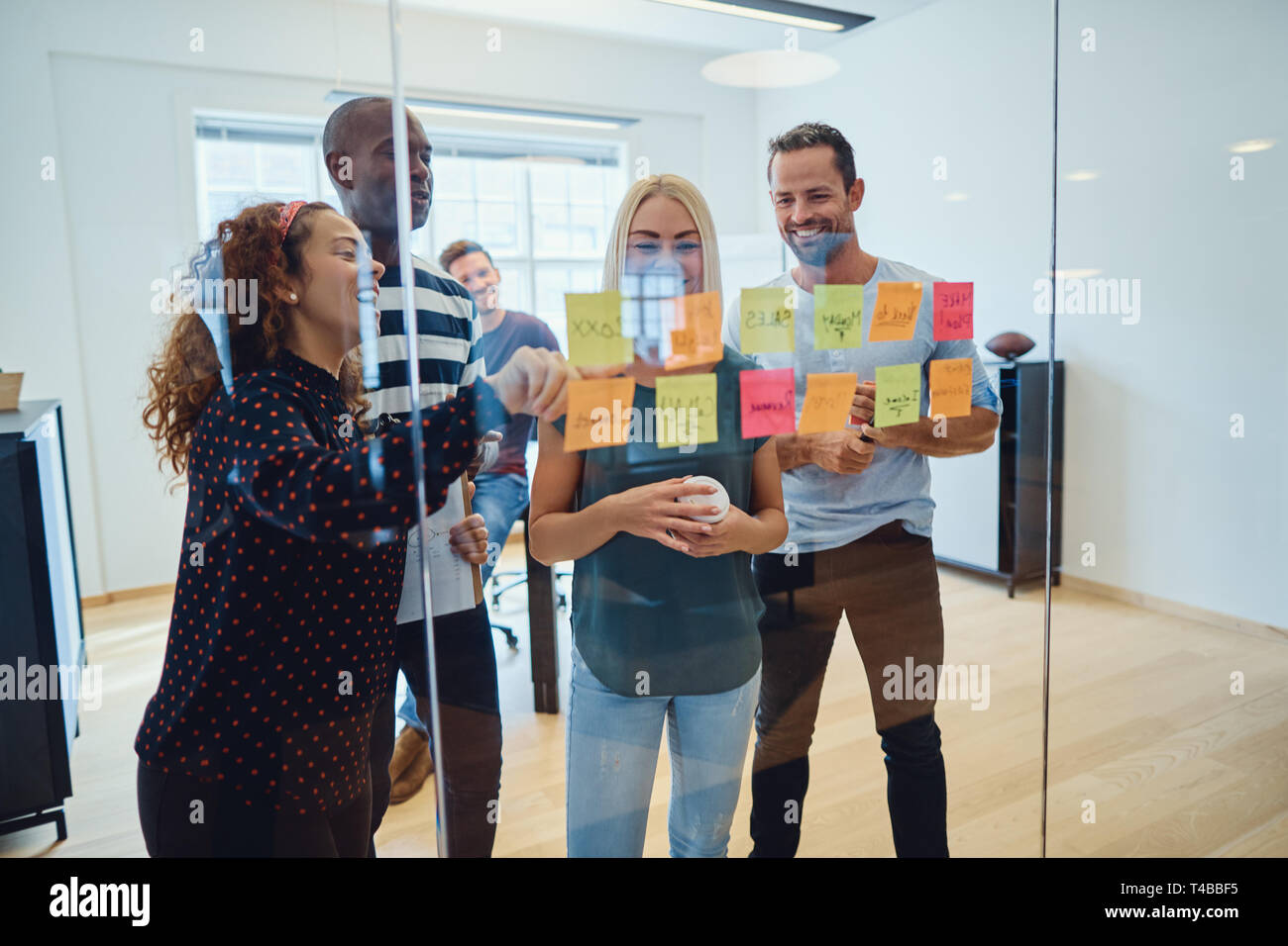 Diverse group of laughing young designers brainstorming together with ...