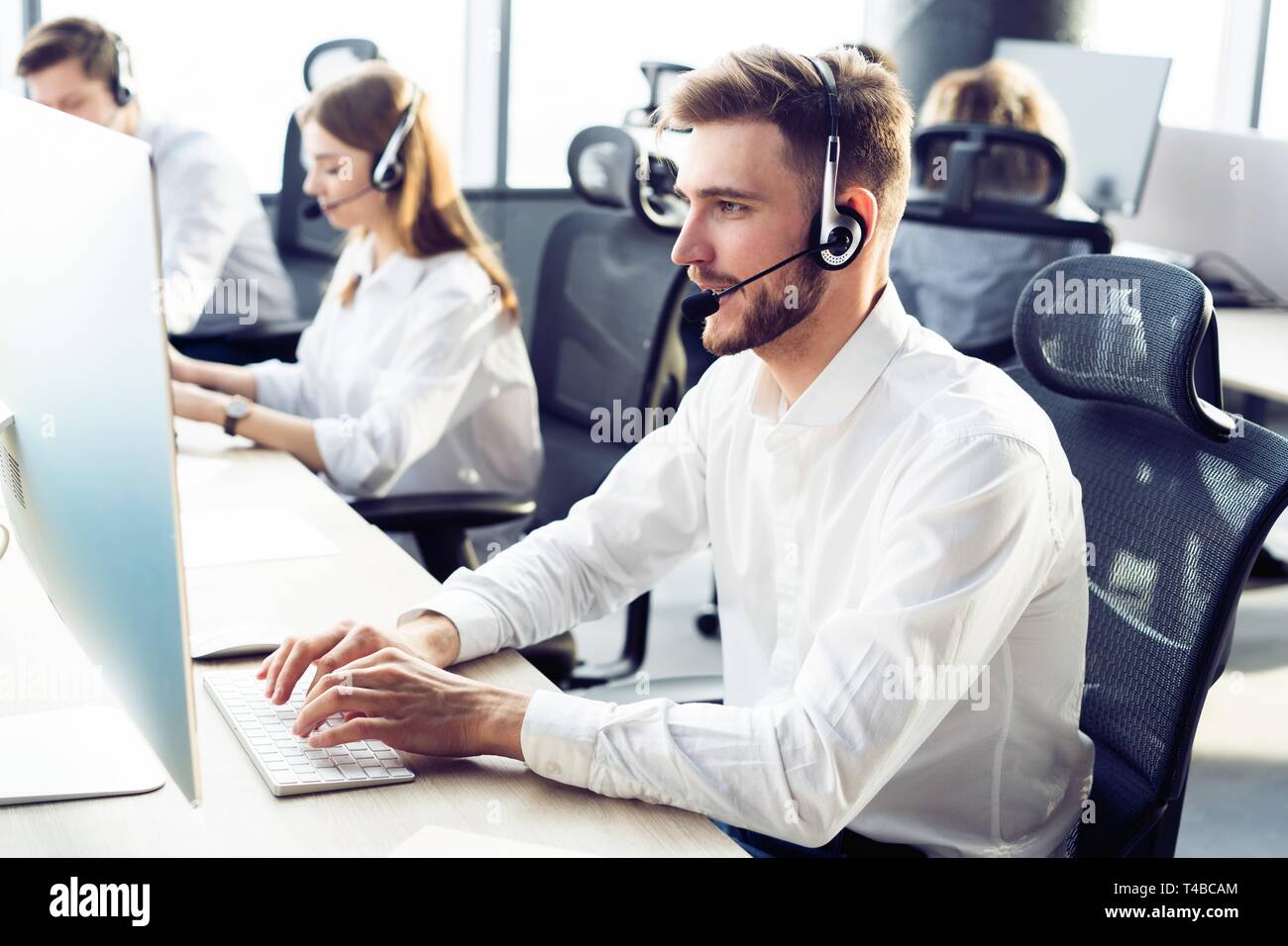 Happy young male customer support executive working in office Stock ...