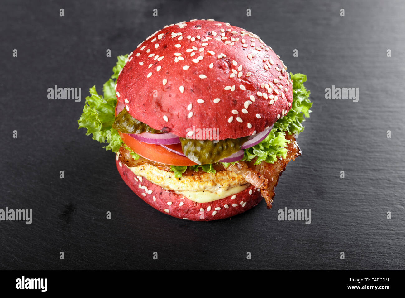 one burger with red bun on a black table. clearly visible texture buns ...