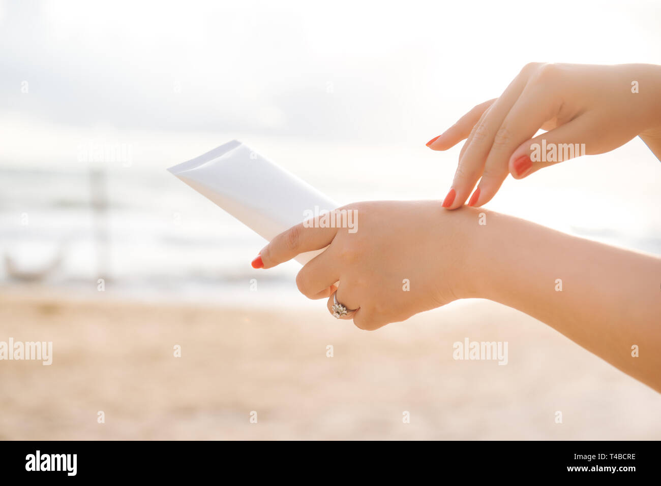 Woman hand holding sunscreen on the beach with the sea in blue sky ...