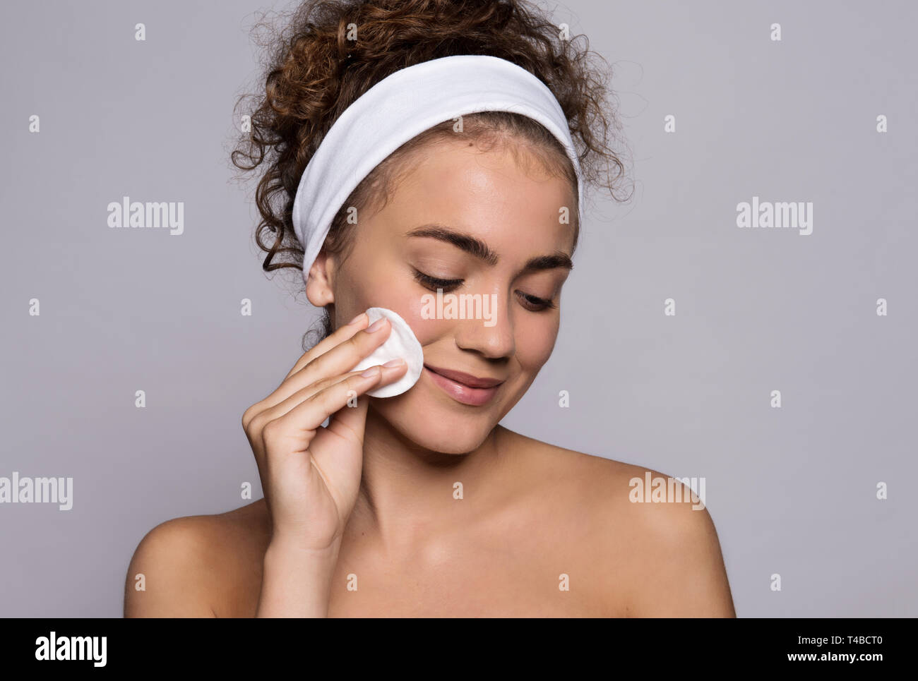 A portrait of a young woman cleaning face in a studio, beauty and skin ...