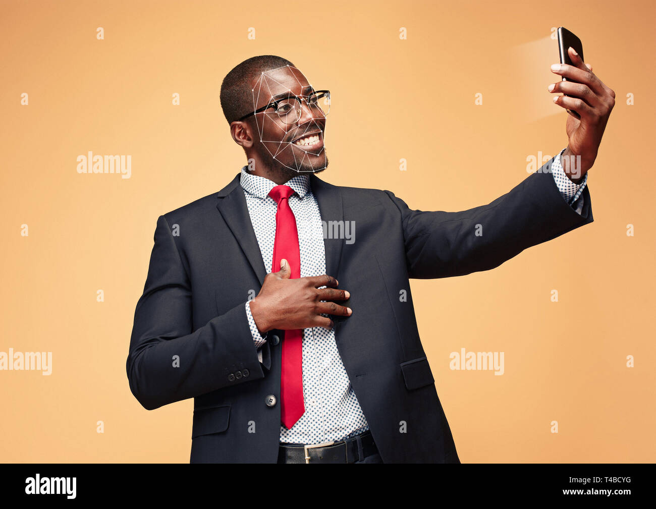 Smile to another world. Young man with a smartphone standing on orange ...