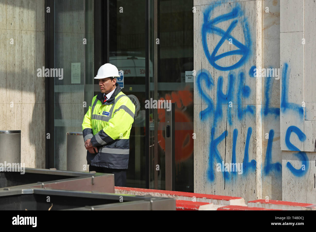 A security guard stands by a graffiti covered Shell building on the ...