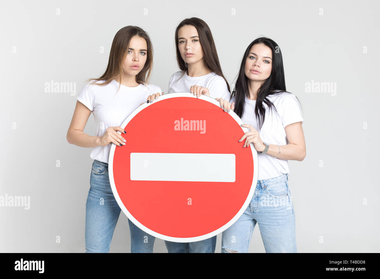 Three beautiful young women hold a big red sign Stock Photo - Alamy