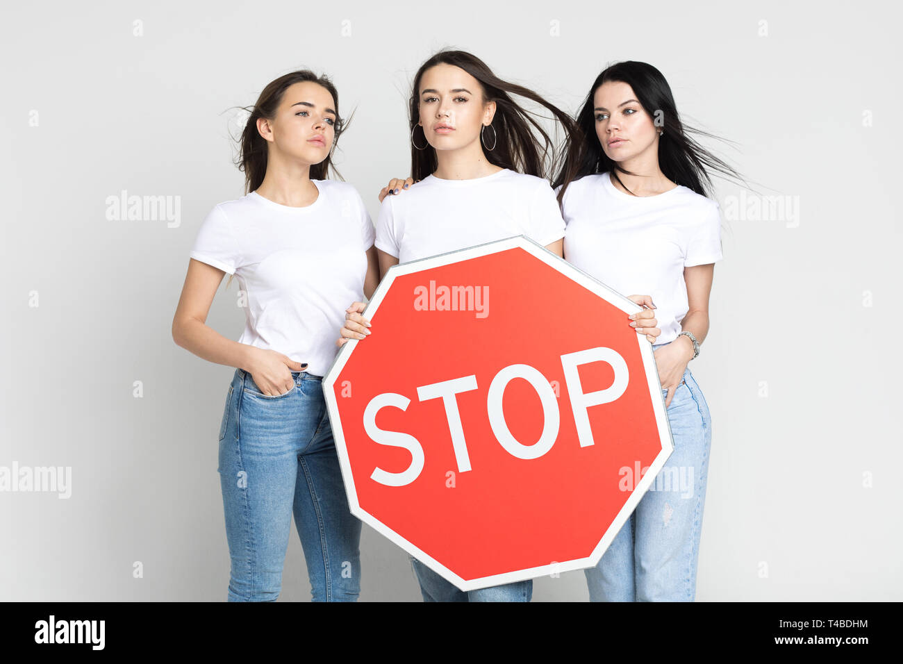 Three beautiful young women hold a big red stop sign Stock Photo - Alamy
