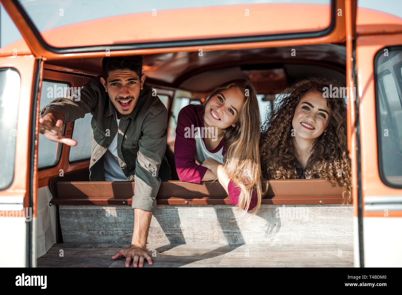 A group of young friends on a roadtrip through countryside, looking out ...