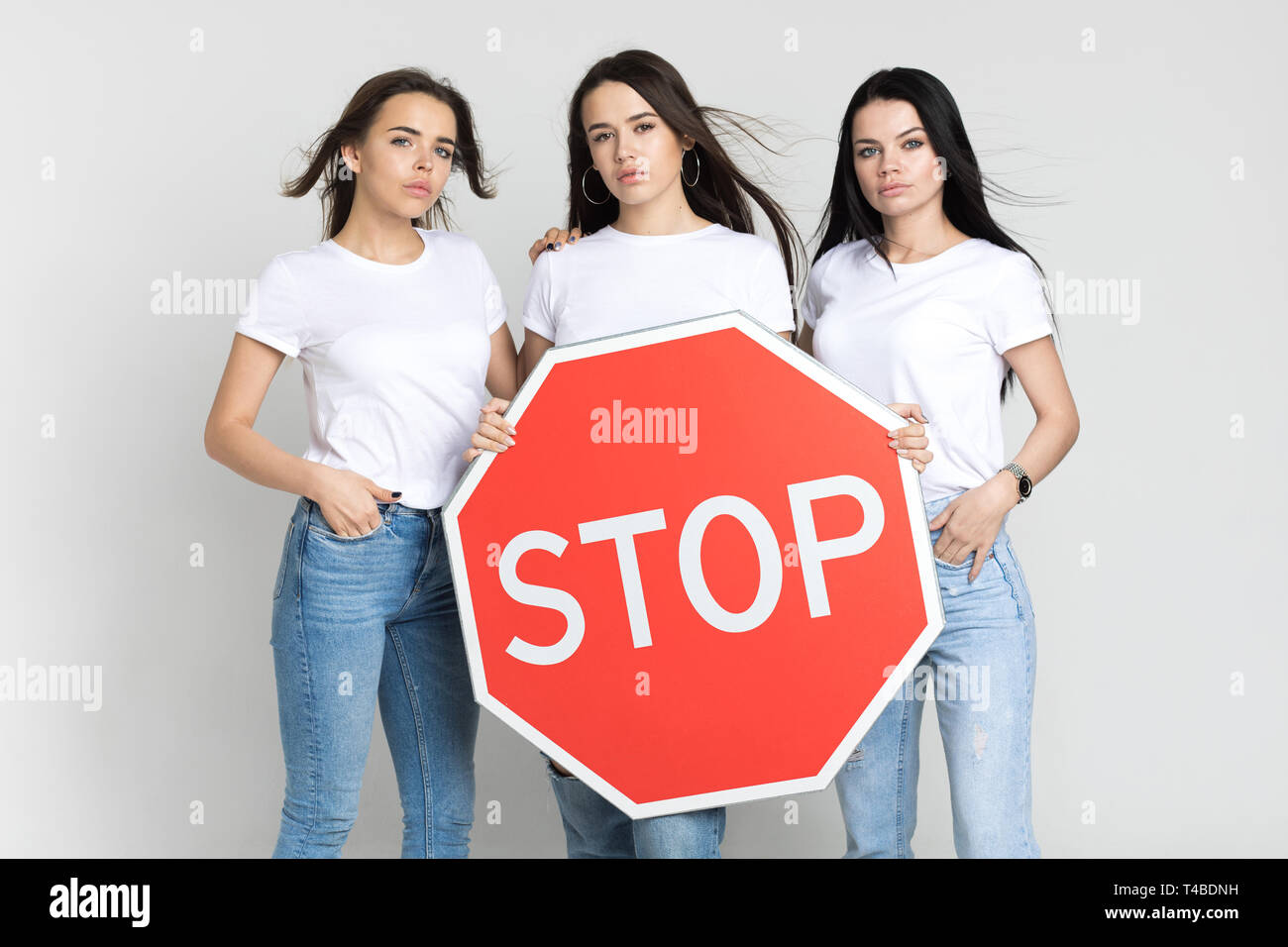 Three beautiful young women hold a big red stop sign Stock Photo - Alamy
