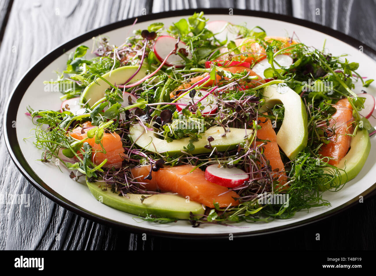 Freshly prepared salad of red fish, avocado, radish and a mix of micro ...