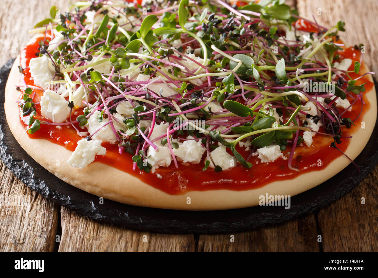 Rustic style pizza with feta and fresh mix micro green close-up on the ...