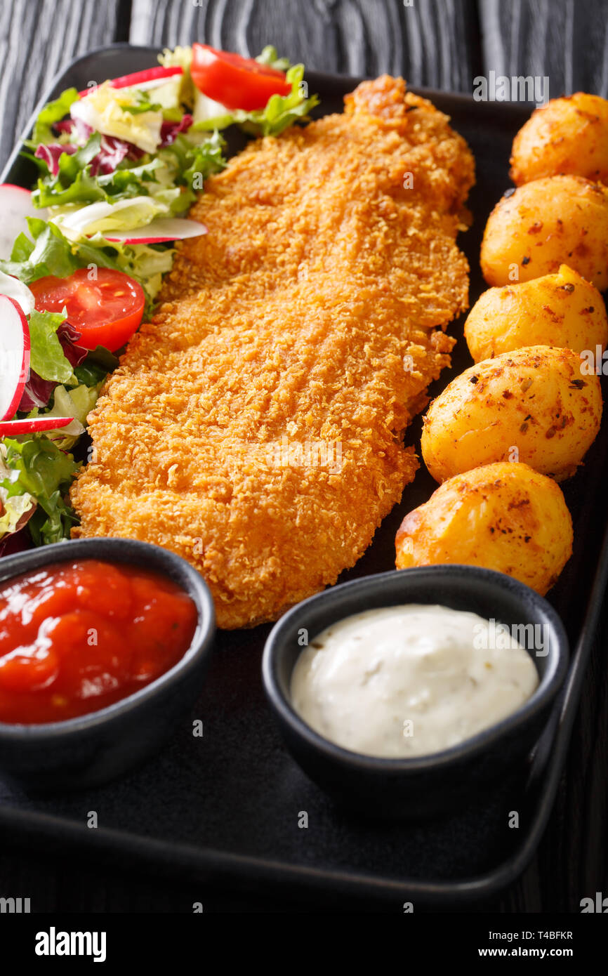 fried cod fillet in breading with a garnish of new potatoes and fresh ...