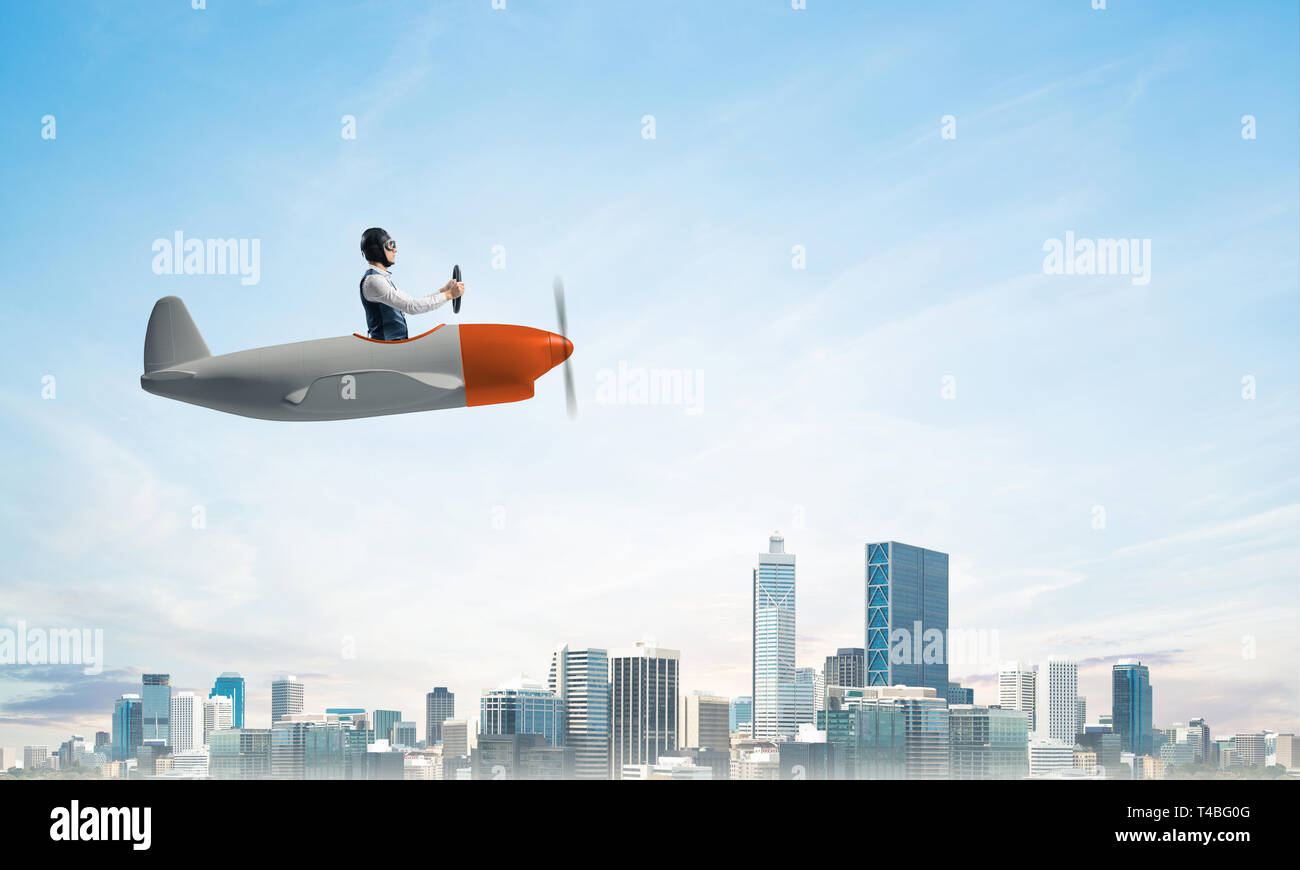 Businessman in aviator hat and goggles driving propeller plane above ...