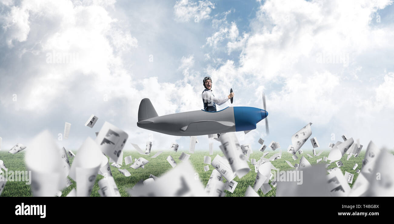 Businessman in aviator hat and goggles driving propeller plane above ...