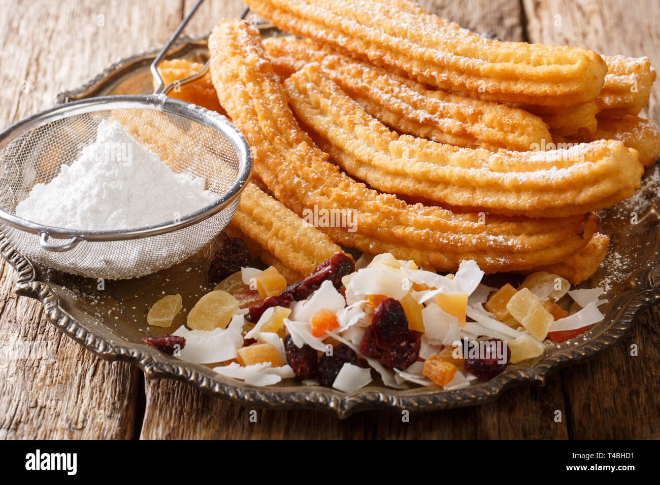 High-calorie deep-fried churros with powdered sugar and candied fruit ...