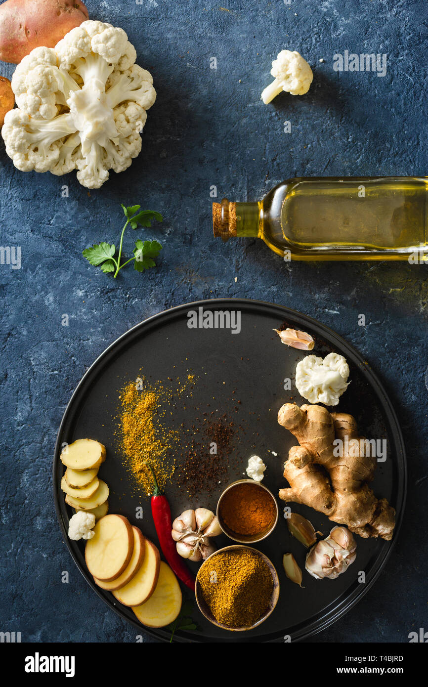 Raw ingredients cooking aloo gobi Indian food on dark stone background ...