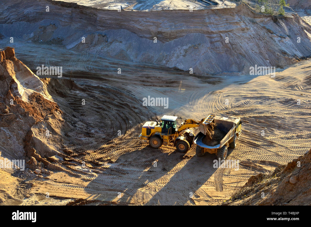 Wheel front-end loader unloading sand into heavy dump truck at the ...