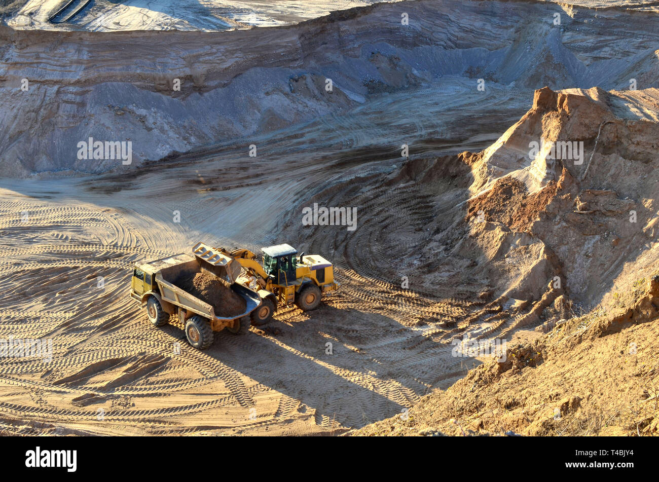 Wheel front-end loader unloading sand into heavy dump truck at the ...