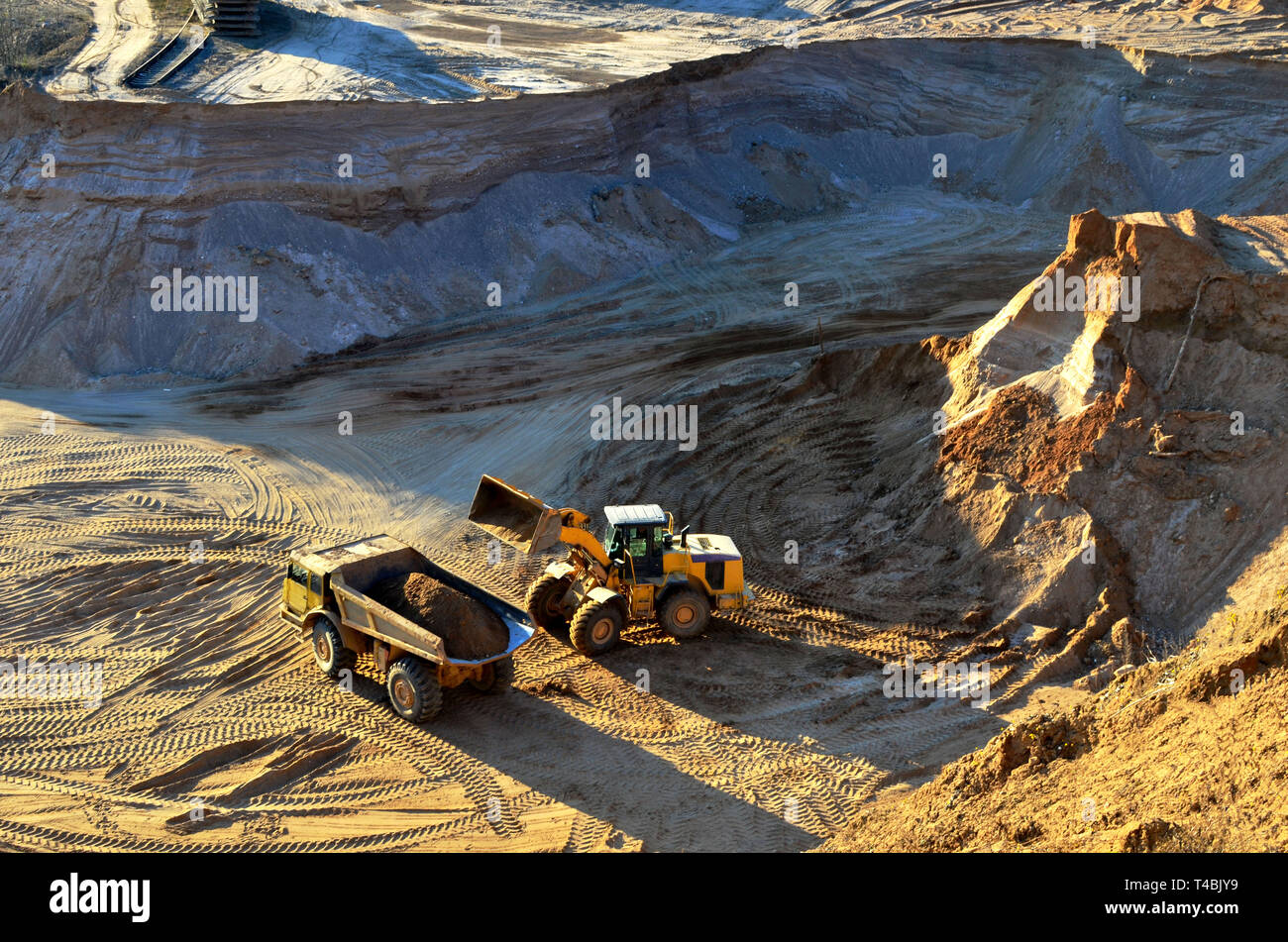 Wheel front-end loader unloading sand into heavy dump truck at the ...