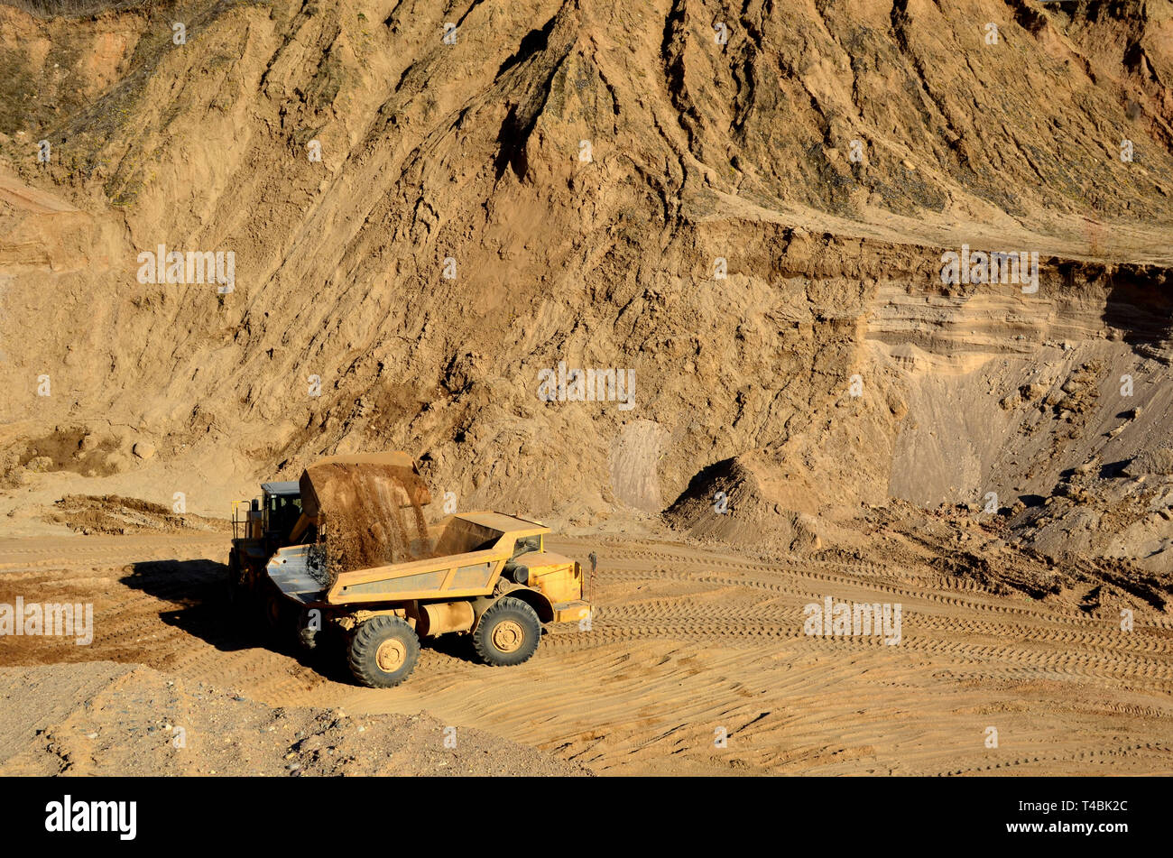Front-end loader loading with sand a heavy dump truck in a mining ...