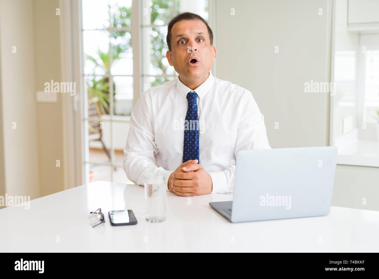 Middle age business man working with computer laptop afraid and shocked ...