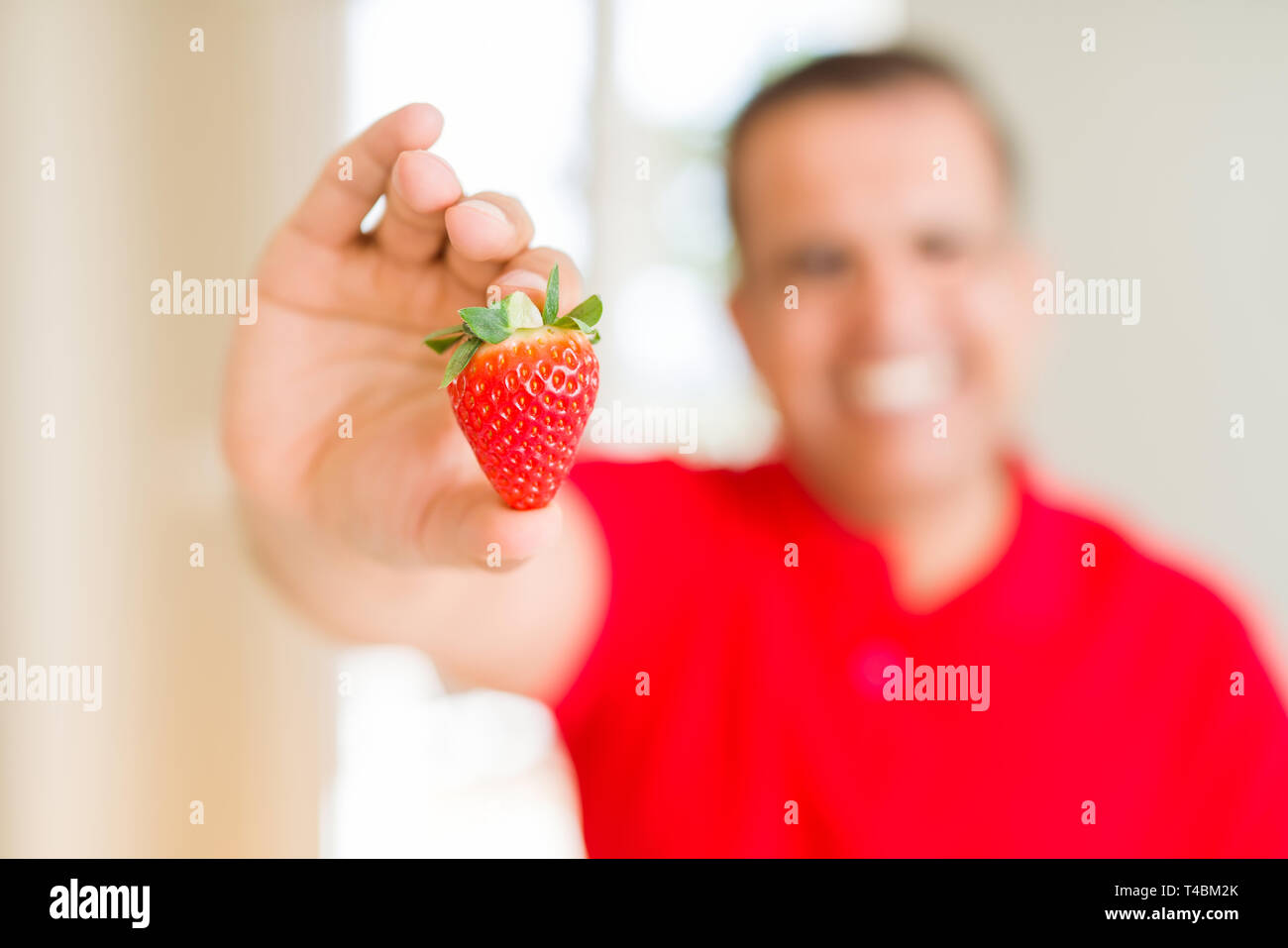 Close up middle age man holding strawberry Stock Photo - Alamy