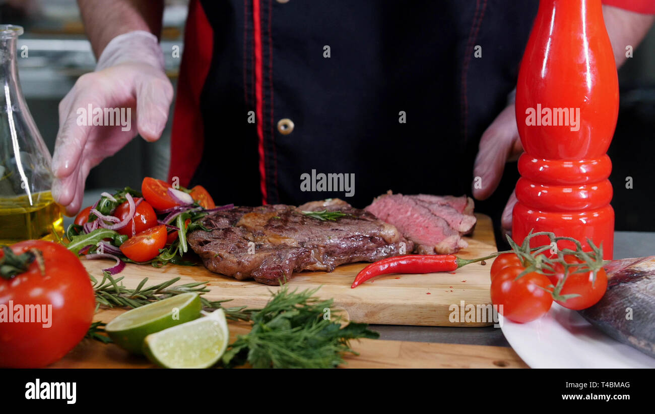 A chef working in the kitchen. A man serving fried steak Stock Photo ...