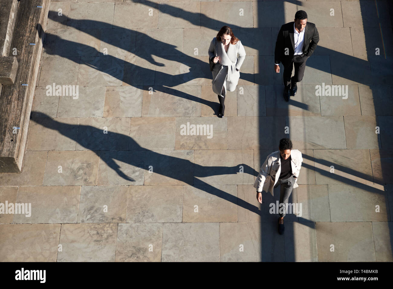 Aerial view of three city workers walking on a sunny urban street ...
