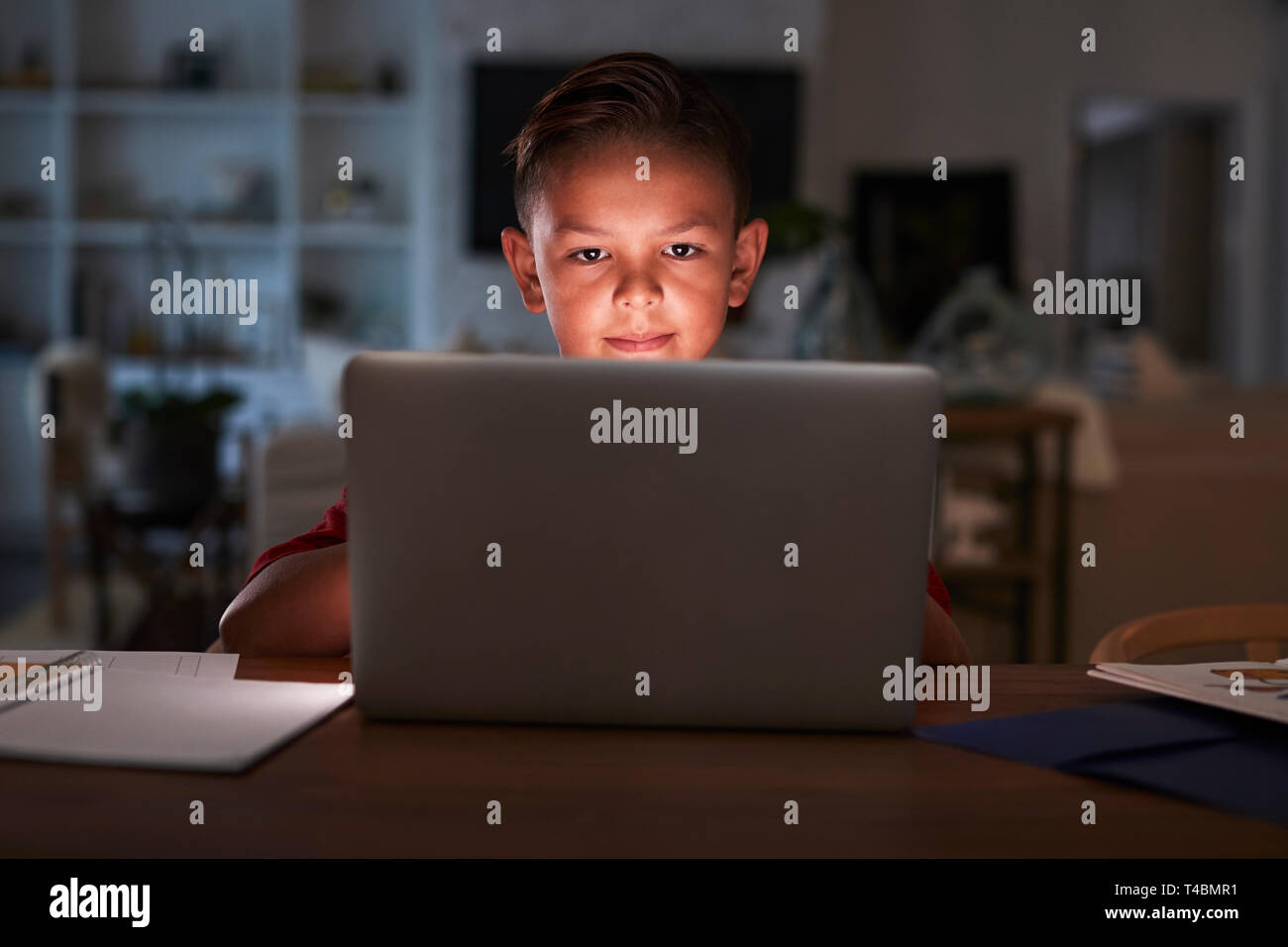 Pre-teen Hispanic boy sitting at dining table doing his homework using ...