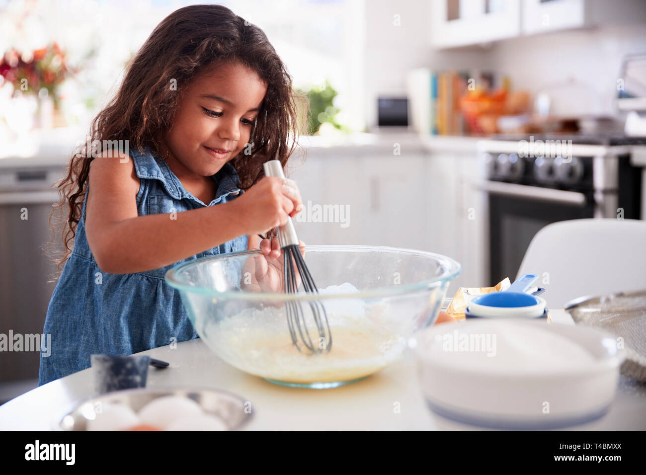 Young Hispanic girl making a cake in the kitchen on her own, close up ...