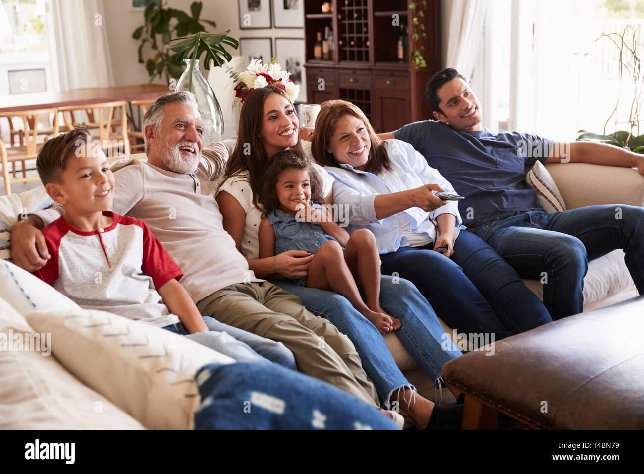Three generation Hispanic family sitting on the sofa watching TV ...