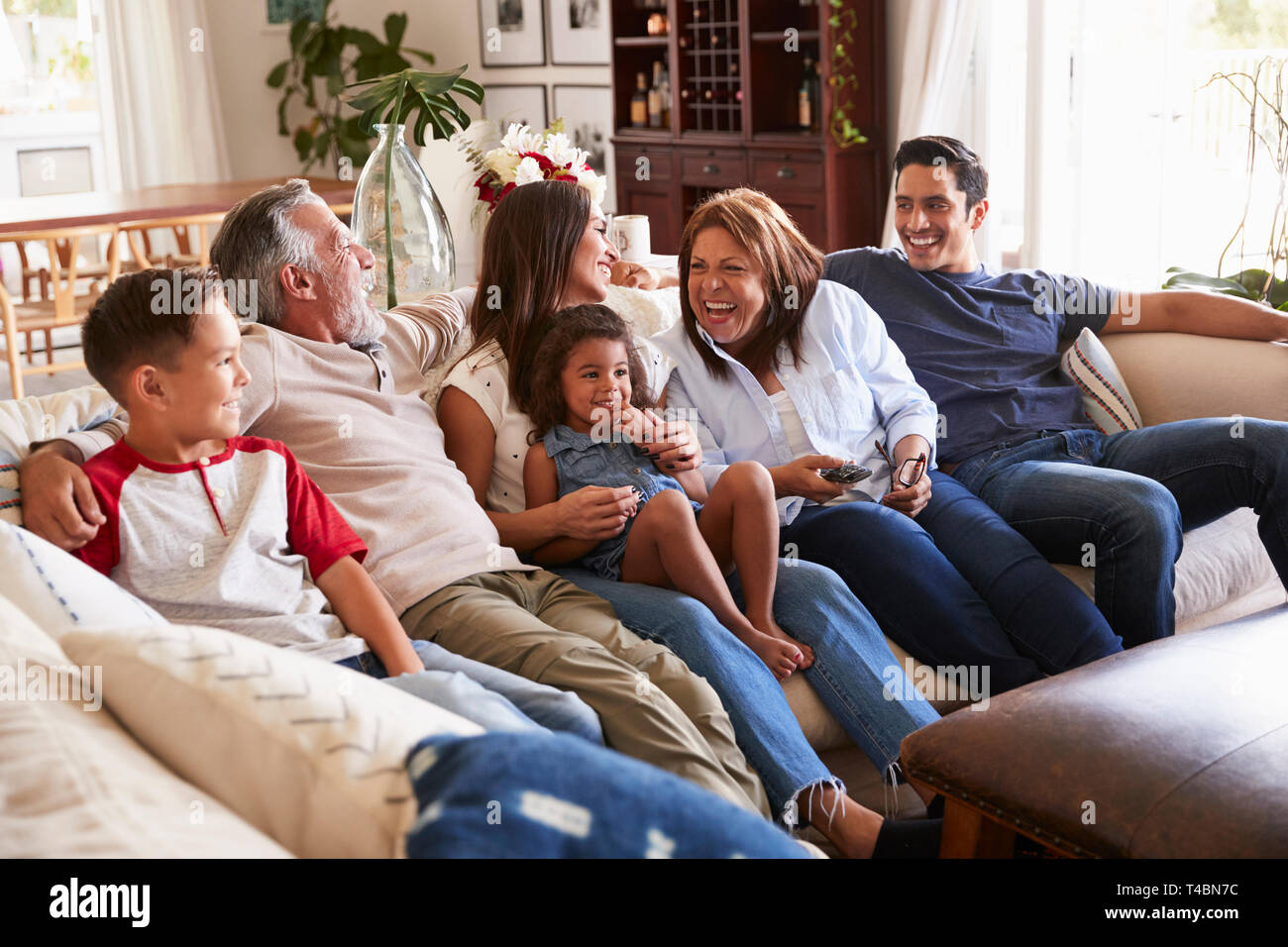 Three generation Hispanic family sitting on the sofa watching TV ...