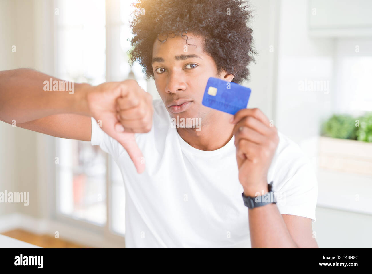 African American man holding credit card with angry face, negative sign ...