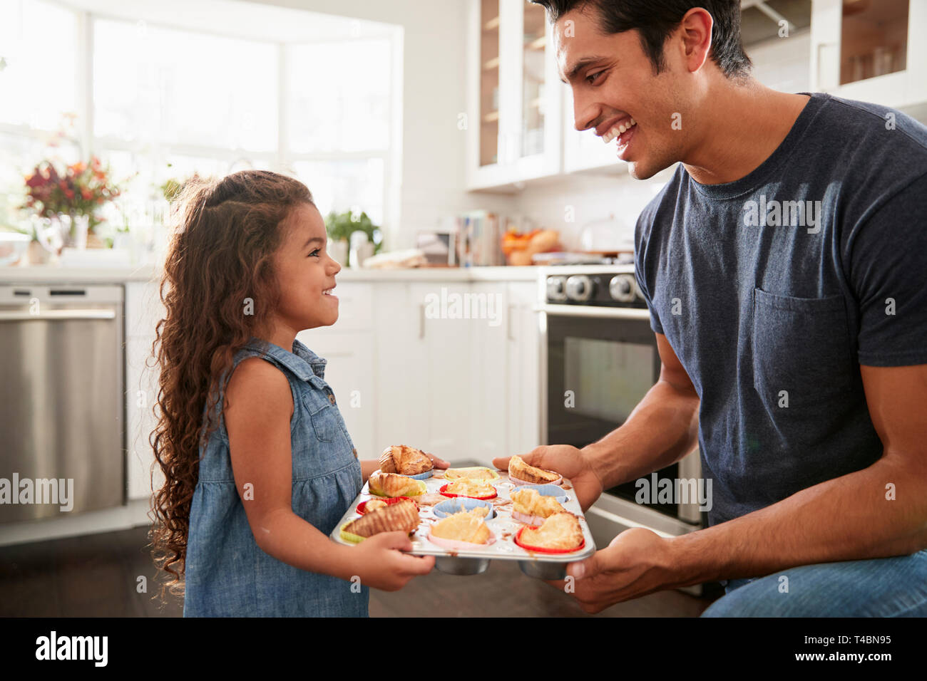 Smiling young Hispanic girl standing in kitchen presenting the cakes ...